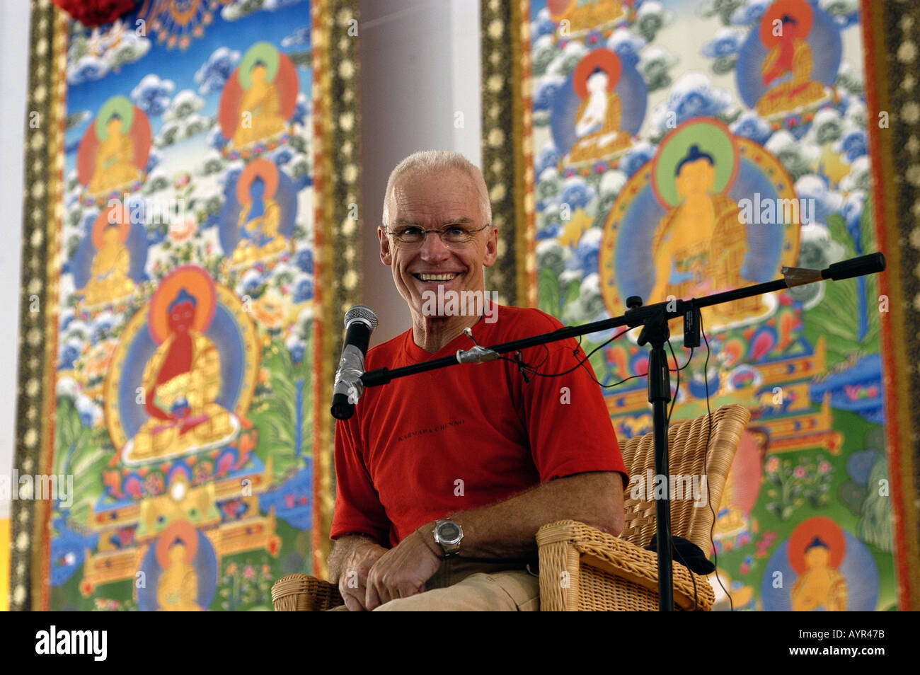 Lama Ole Nydahl smiling in front of large Tibetan Buddhist thangkas ...