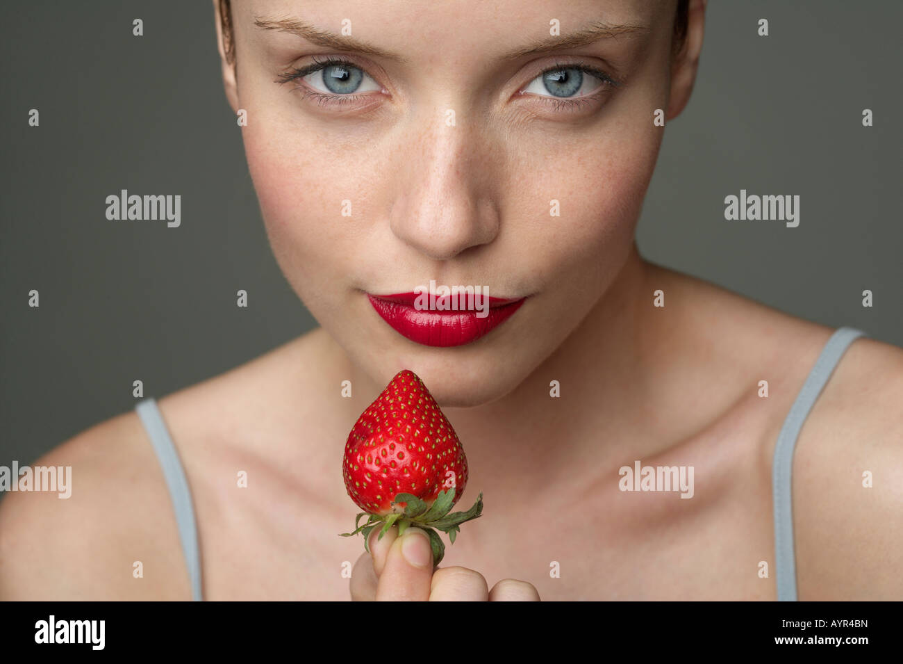 Young woman with a red strawberry under her red lips (part of), close ...