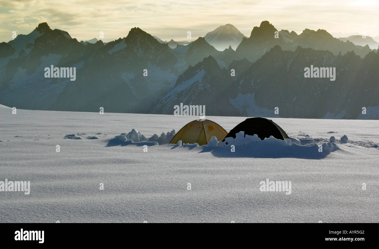 A camp of two tents high in the French Alps with the Swiss Alps behind ...