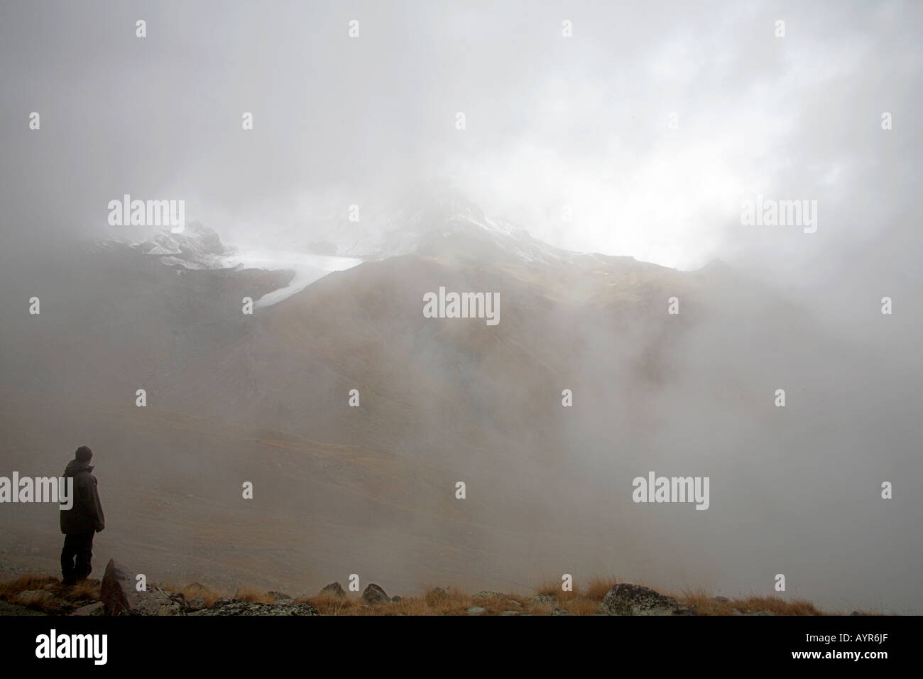 Climber looking up to Mount Kazbek in mist, Georgia Stock Photo - Alamy