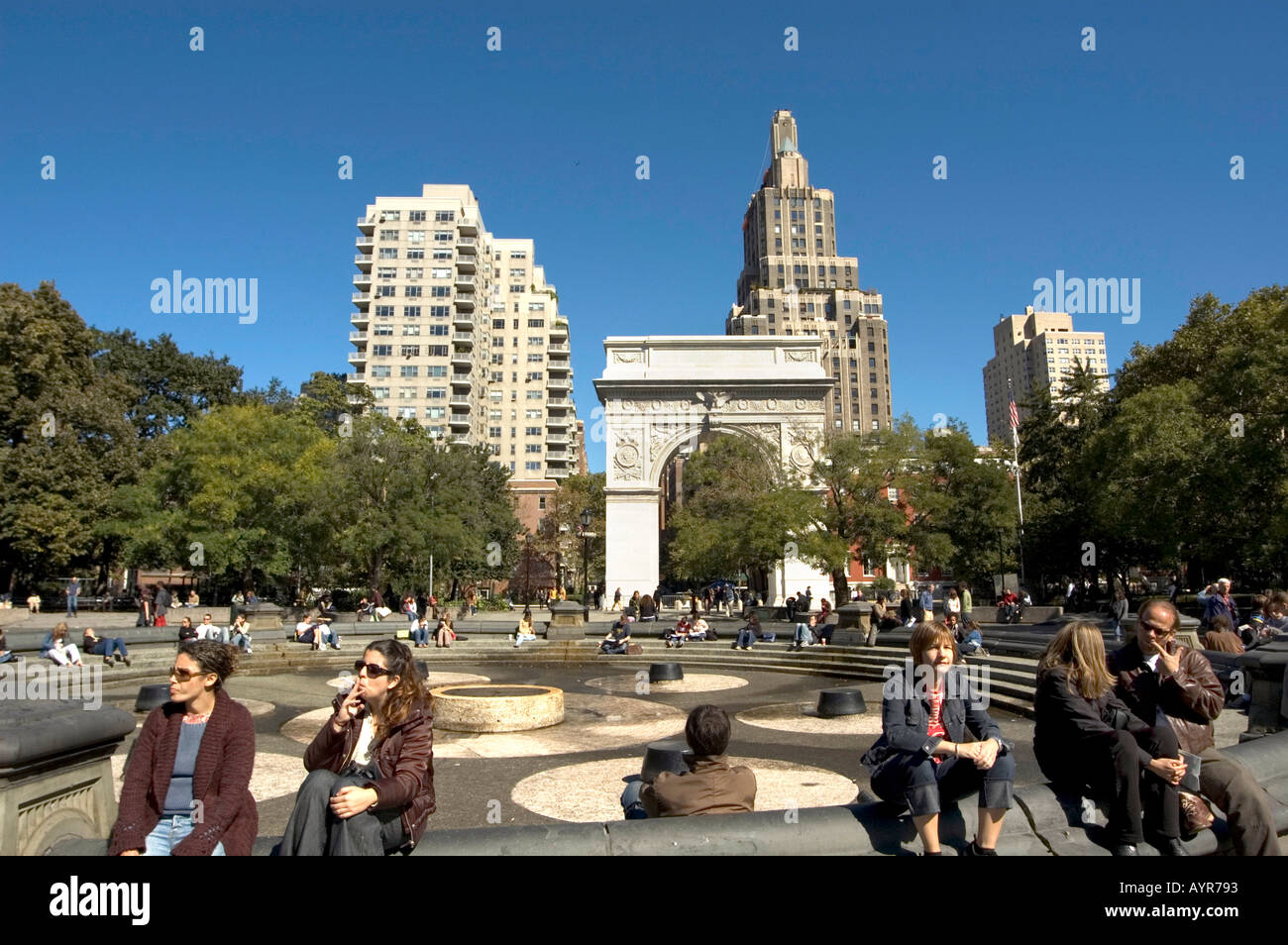 PEOPLE SITTING IN THE SUN DURING LUNCHTIME AT WASHINGTON SQUARE LOWER ...
