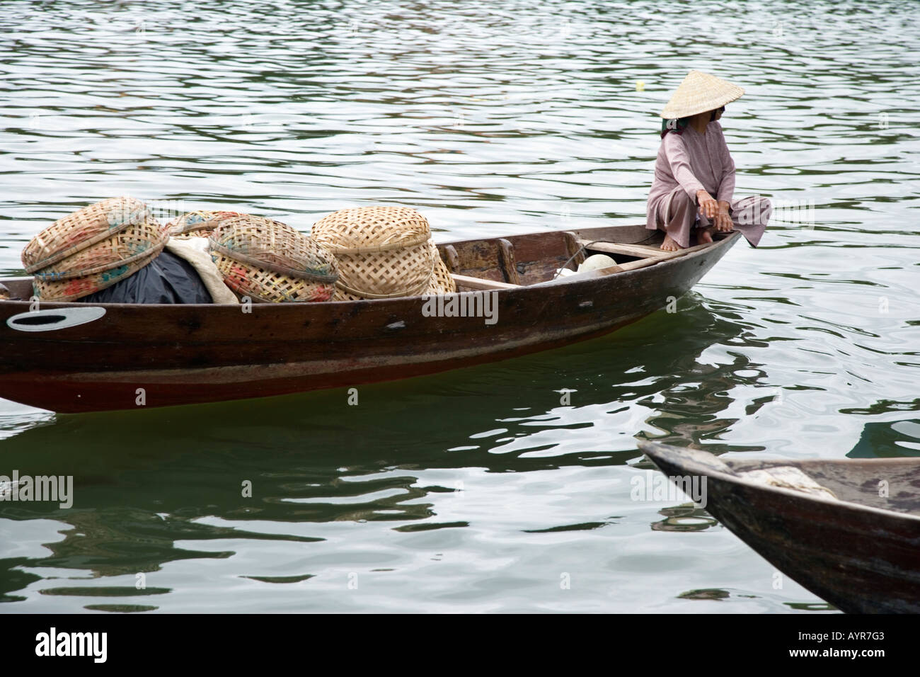 Woman wears conical hat in stern of boat with baskets, Hoi An, Vietnam ...