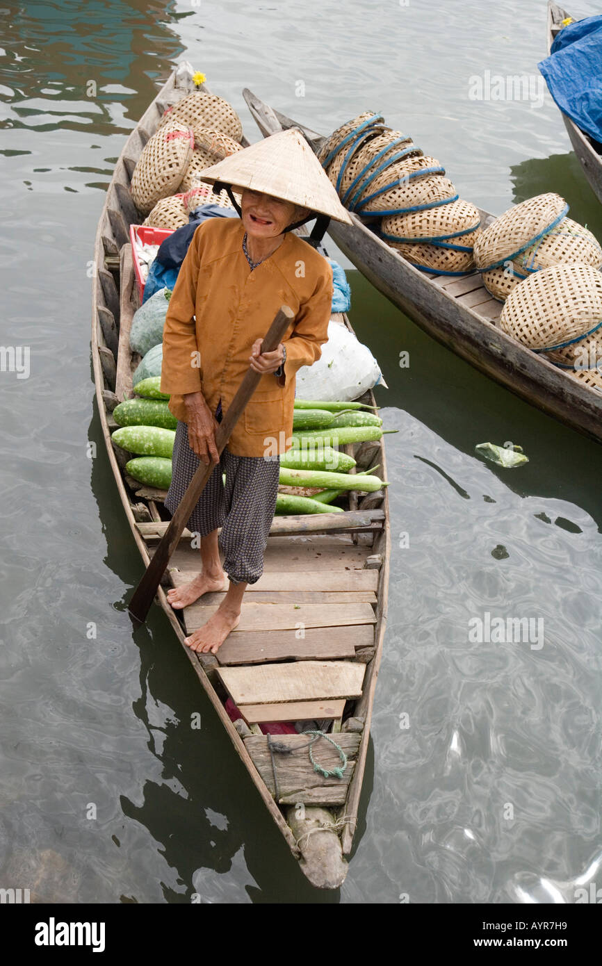 Aged woman with conical hat in wooden boat with produce, Hoi An ...