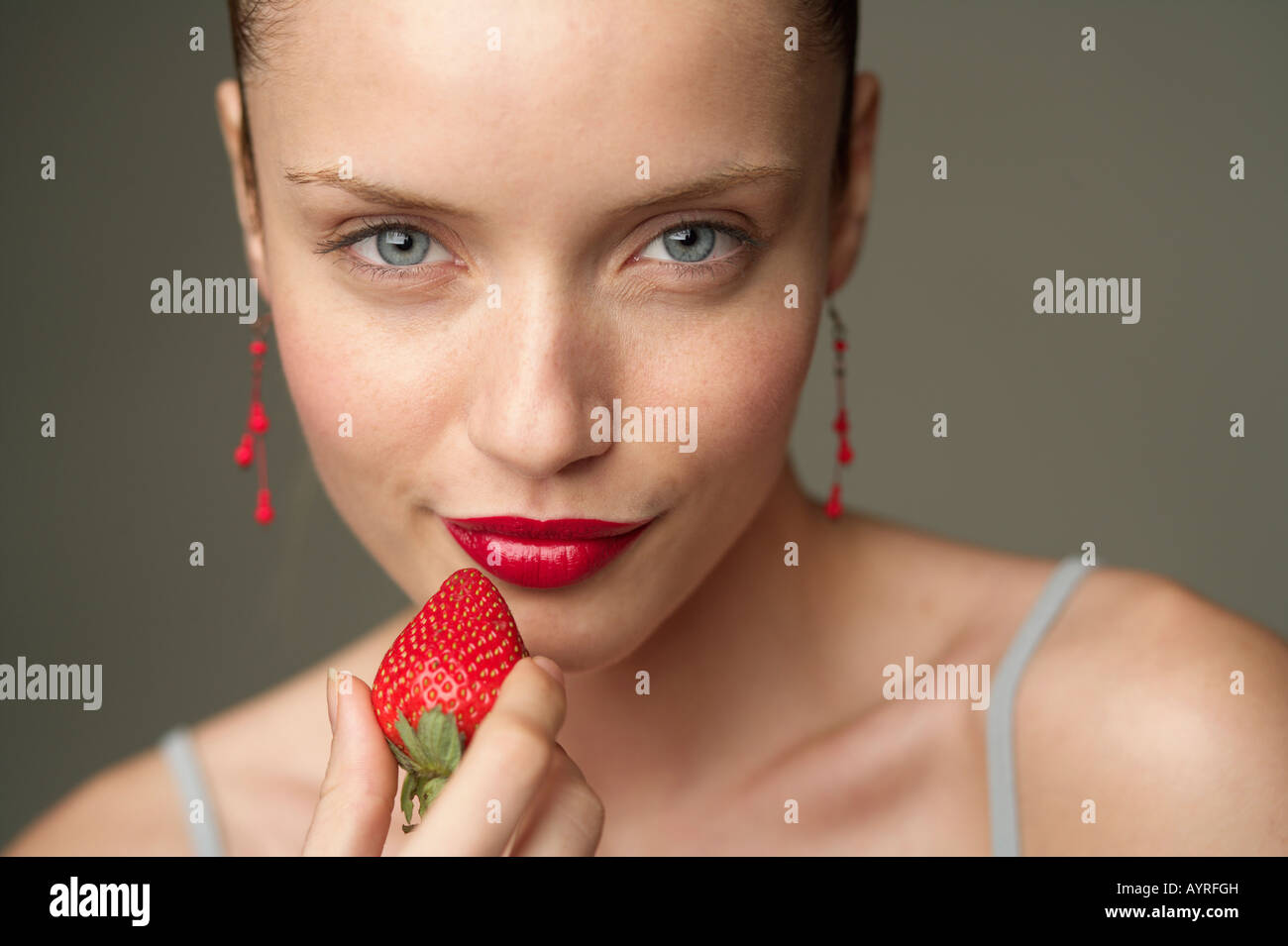 Young woman with a red strawberry under her red lips (part of), close ...