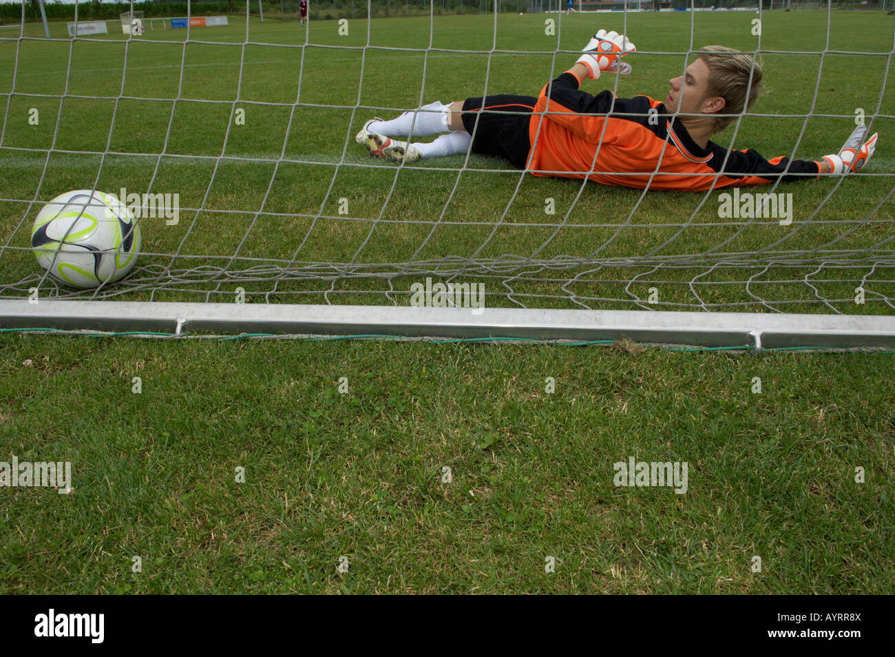 Goalkeeper lying on ground, ball in net Stock Photo - Alamy