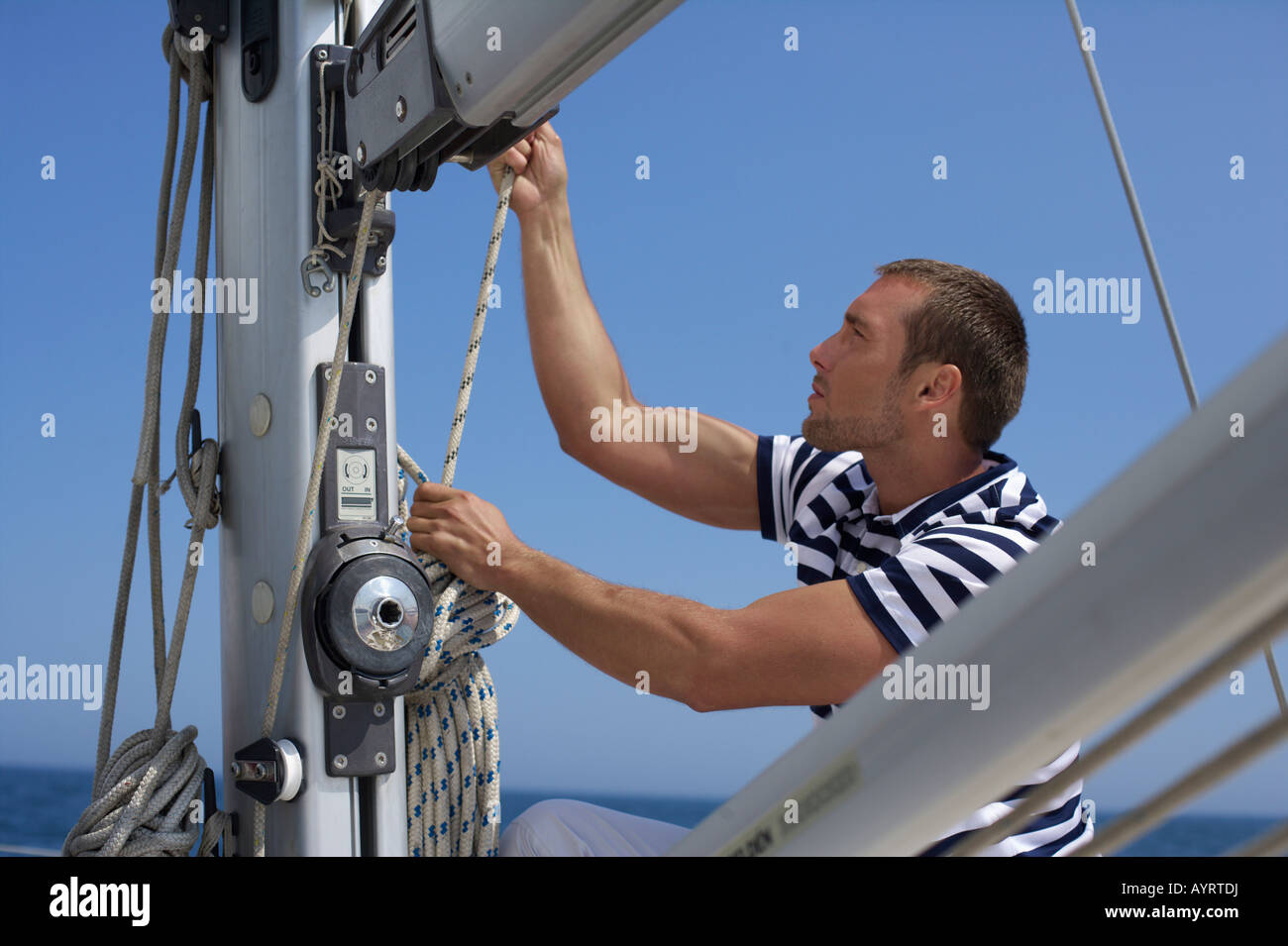 Young adult man is pulling a rope on a sailing boat Stock Photo - Alamy