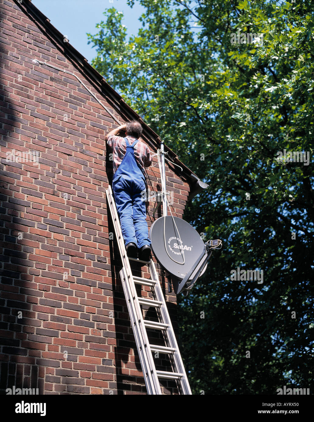 fitter assambles parabolic antenna at an outside wall, parabolic ...