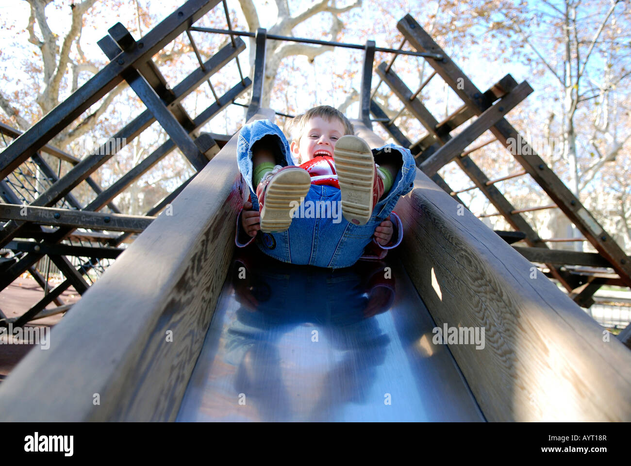 looking up a park slide at a young boy coming down with his feet in the ...