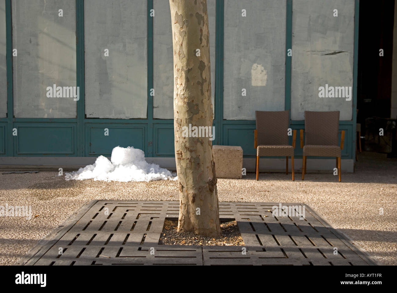 a pile of disregarded ice cubes and a pair of empty chairs sit outside ...