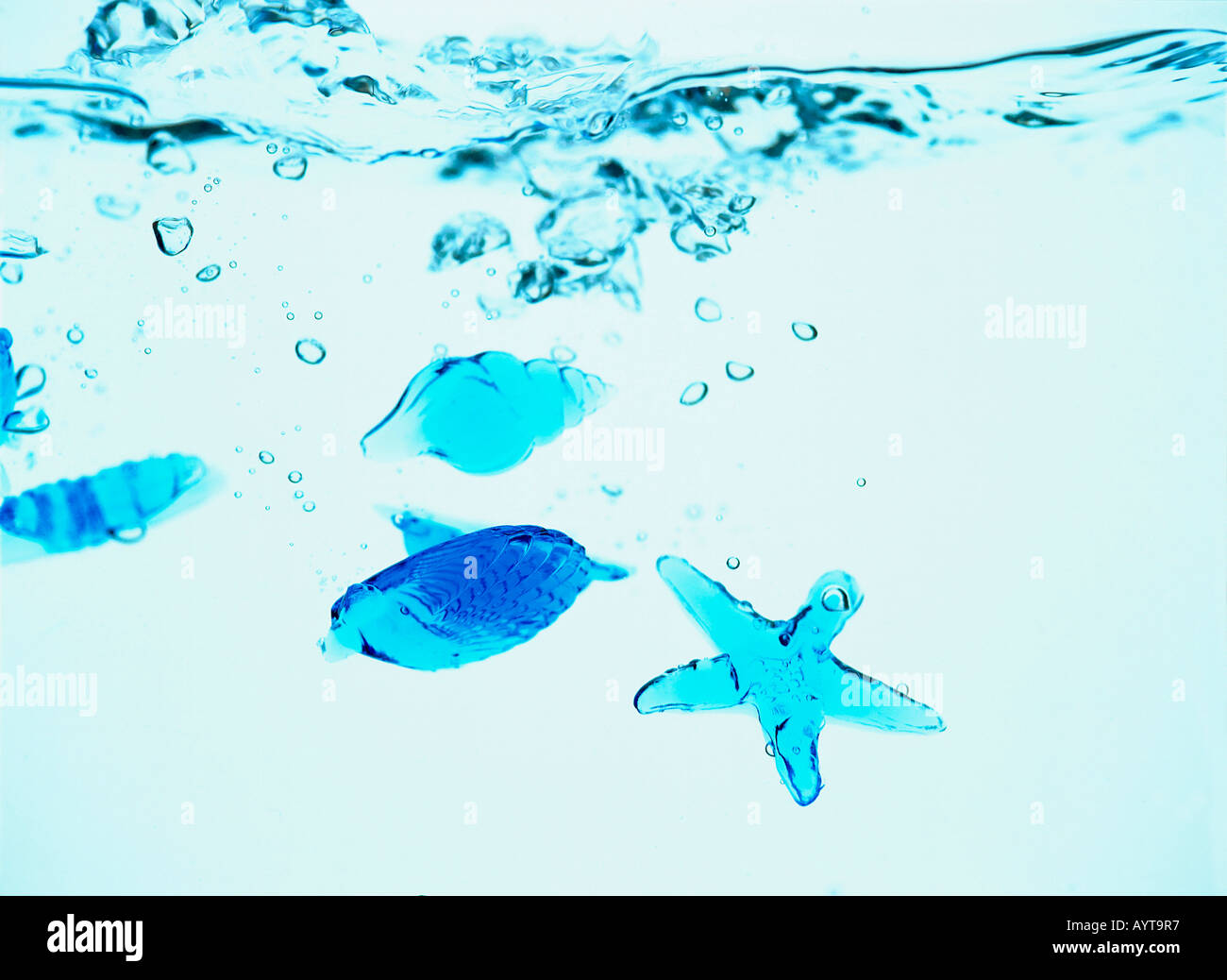 Transparent light blue shells dropped inside water creating bubbles ...