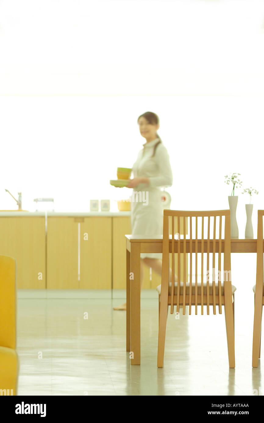 Woman carrying dishes in the kitchen Stock Photo - Alamy