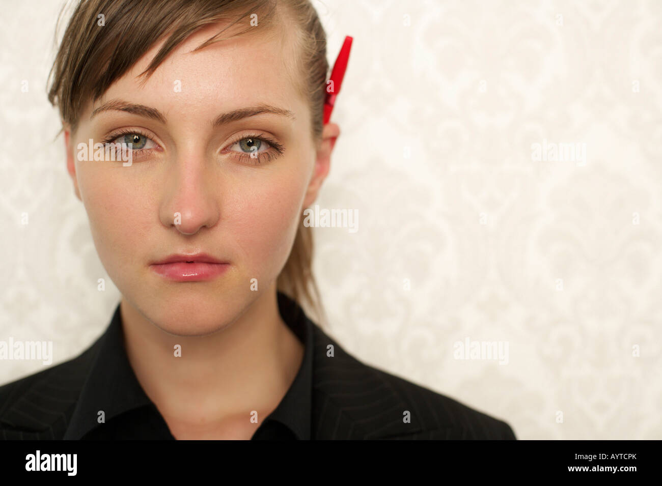 Businesswoman with pen behind ear looking at camera Stock Photo - Alamy