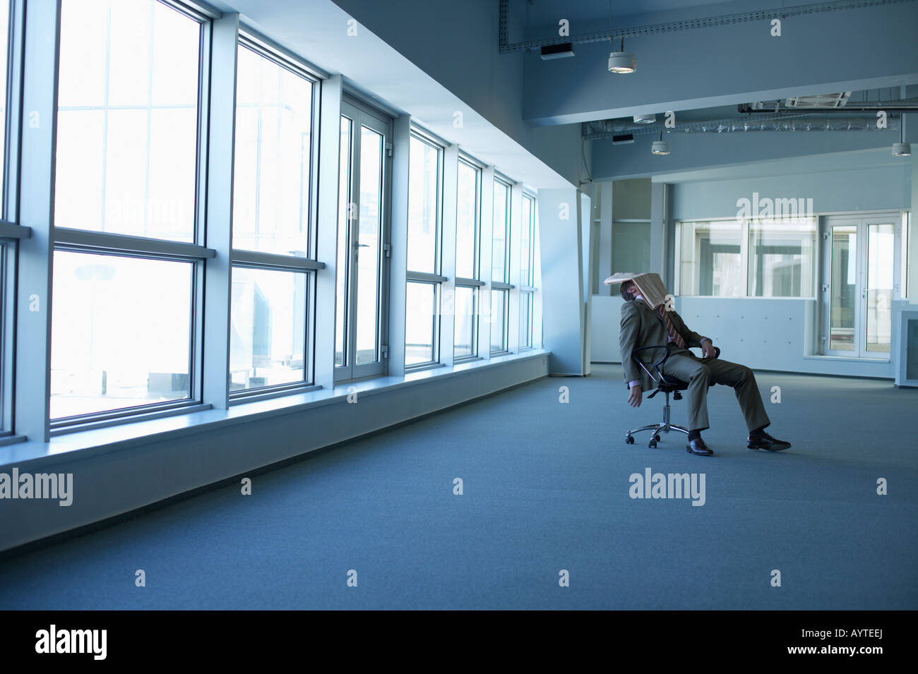 Exhausted businessman sitting in an empty office Stock Photo - Alamy