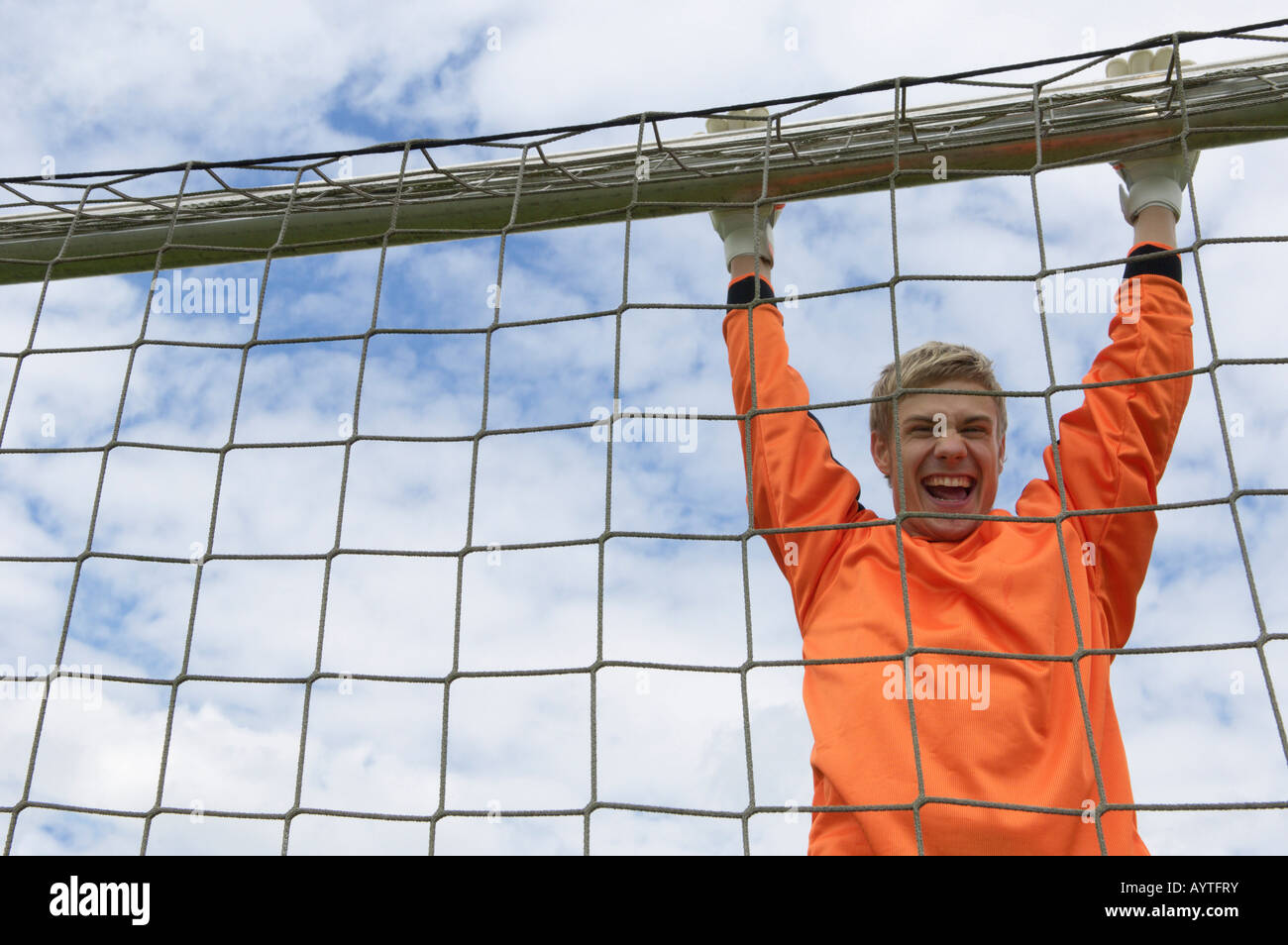 Cheering goalkeeper hanging on goal Stock Photo - Alamy