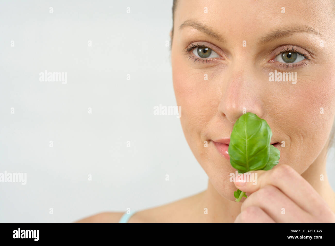 Mid adult woman smelling a basil leaf Stock Photo - Alamy