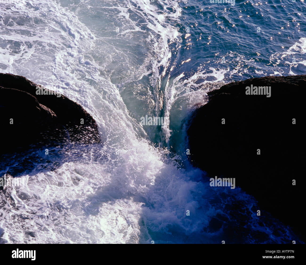 wave flowing through gap in rocks Stock Photo - Alamy