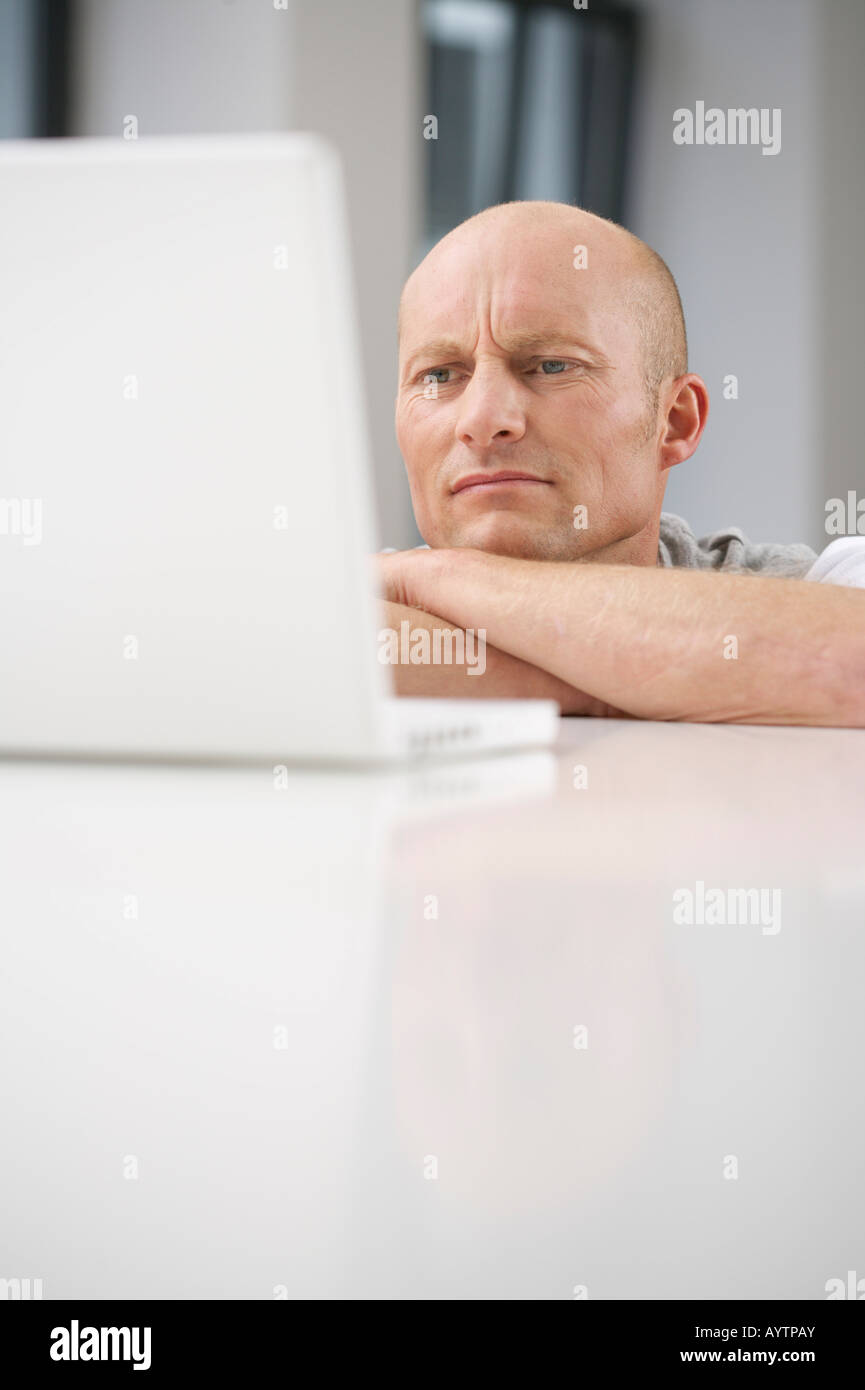 Reflective businessman crouching at a table with a laptop Stock Photo ...