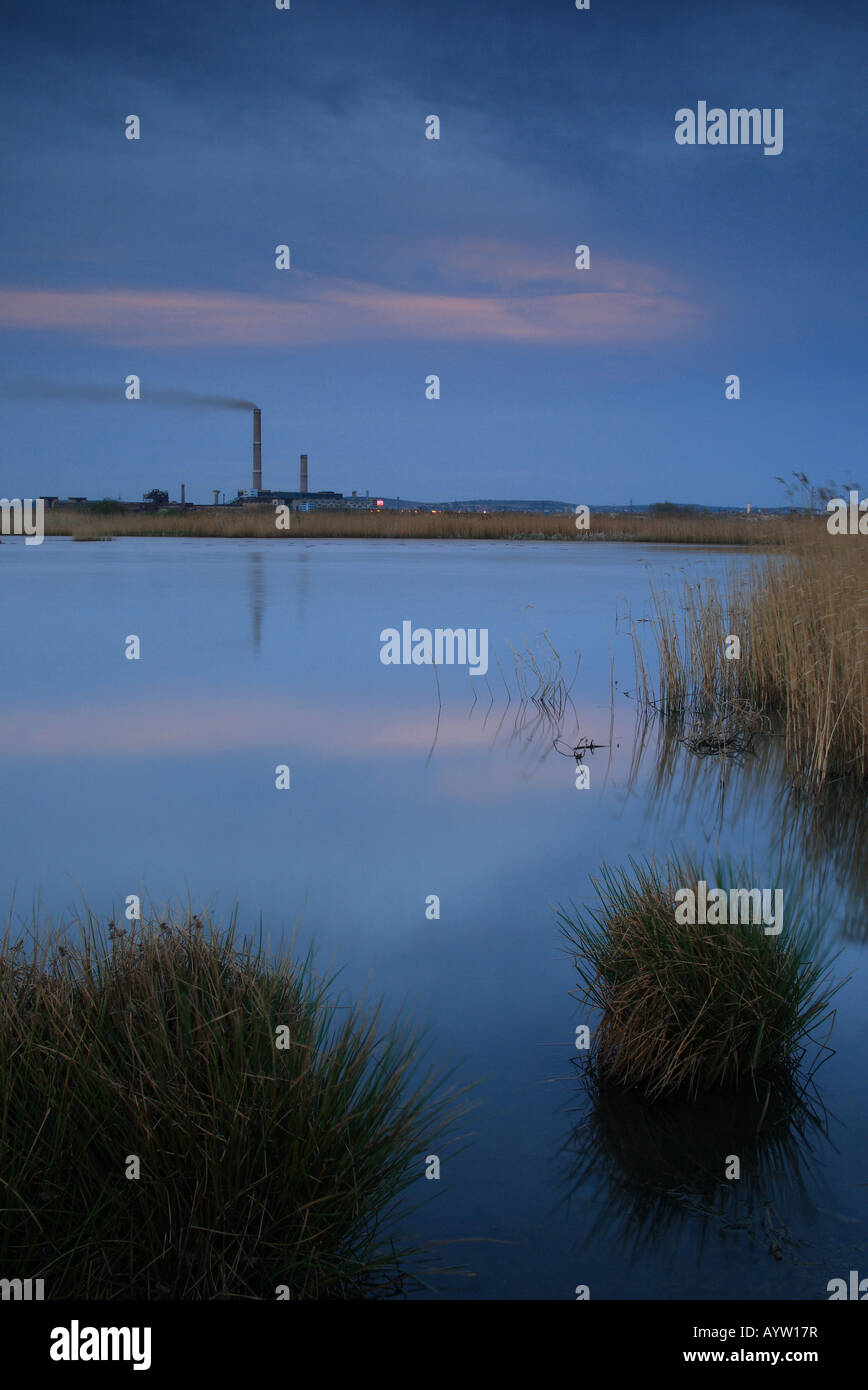 A quiet lake at sunset with the smoke of the factory behind it Stock ...