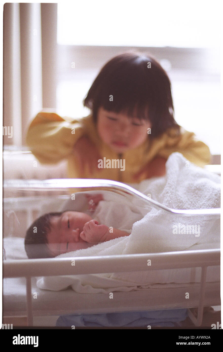 Girl looking into a new born baby Stock Photo - Alamy
