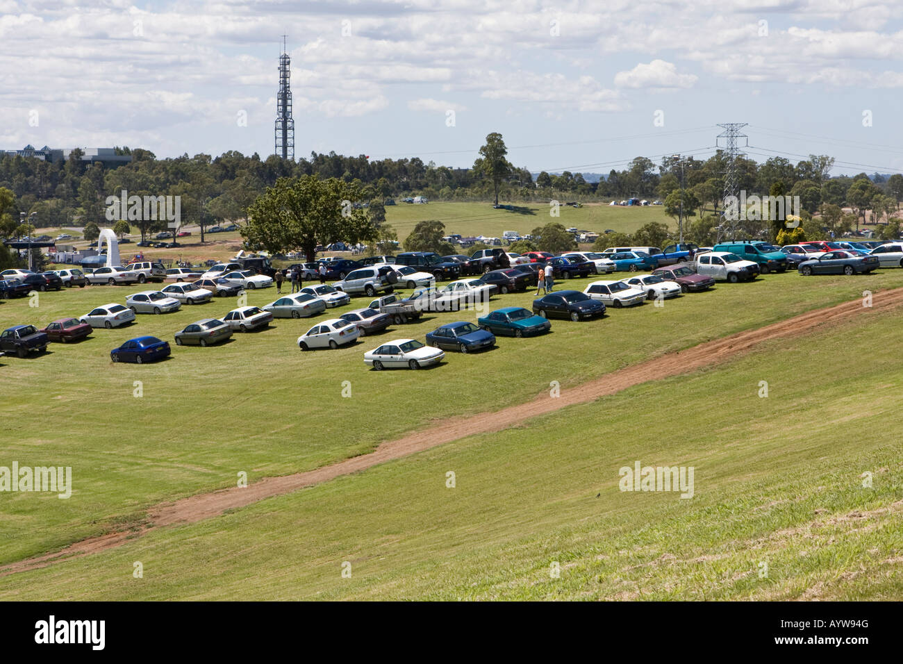 Spectator cars parked on a hillside with a tower in the background ...