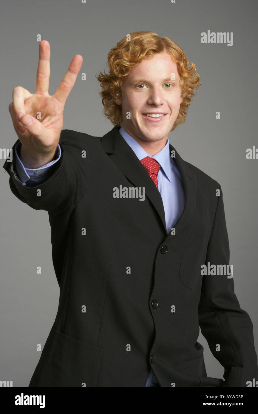 Businessman making peace sign Stock Photo - Alamy