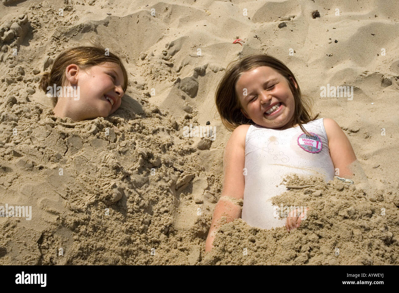 Two young girls play in the sand on holiday Stock Photo - Alamy