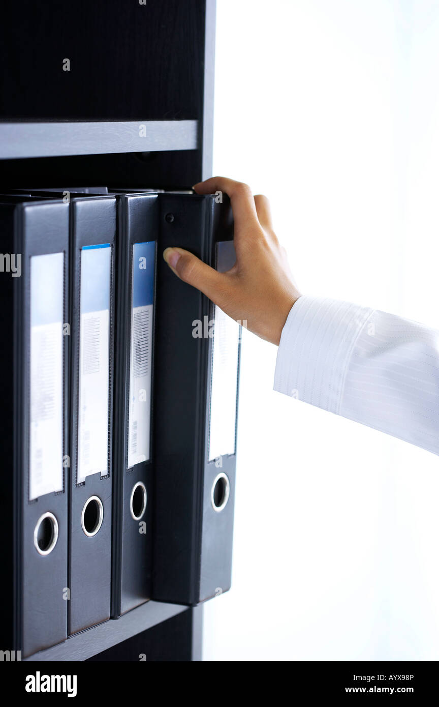 hand taking out black document file from bookself Stock Photo - Alamy