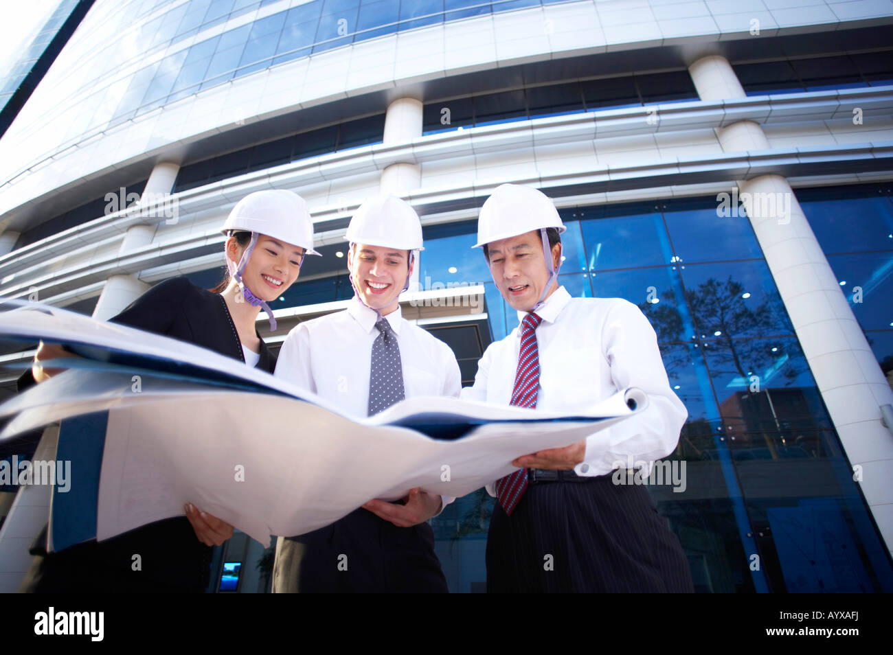 men looking at blueprint in front of building Stock Photo - Alamy