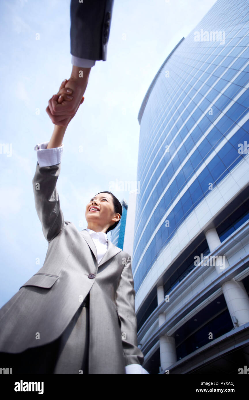 man shaking hands in front of building at low angle Stock Photo - Alamy