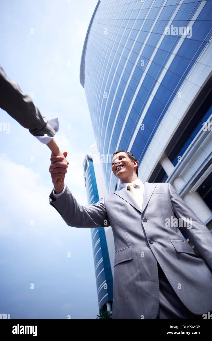 man shaking hands in front of building at low angle Stock Photo - Alamy
