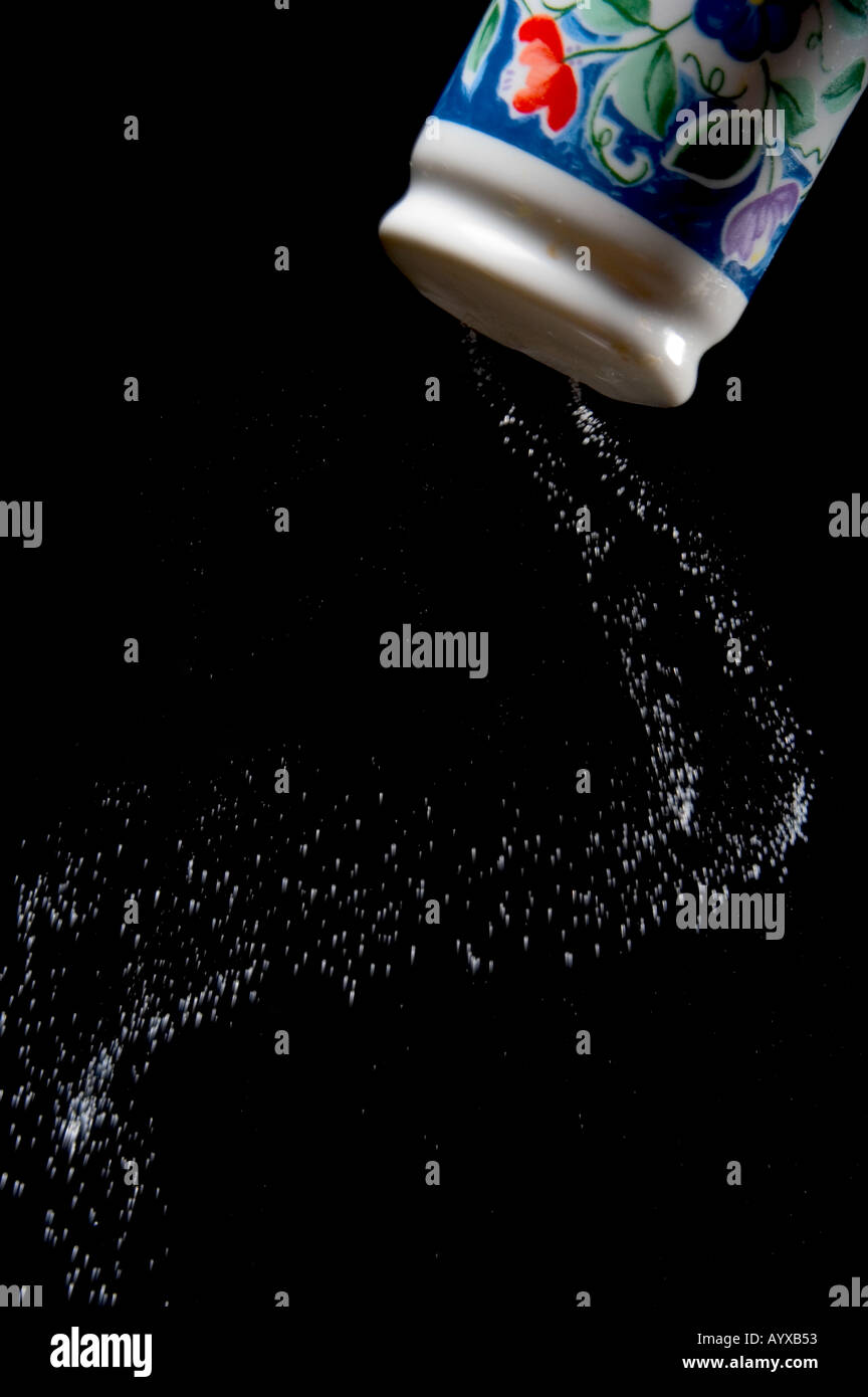 Salt pouring from salt shaker in action shot on black background Stock ...