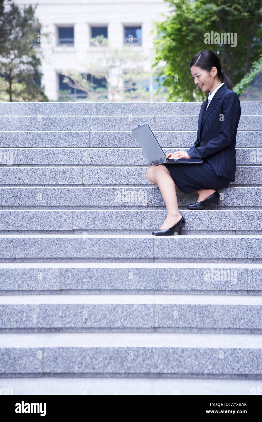 a woman sitting on steps with using laptop computer Stock Photo - Alamy