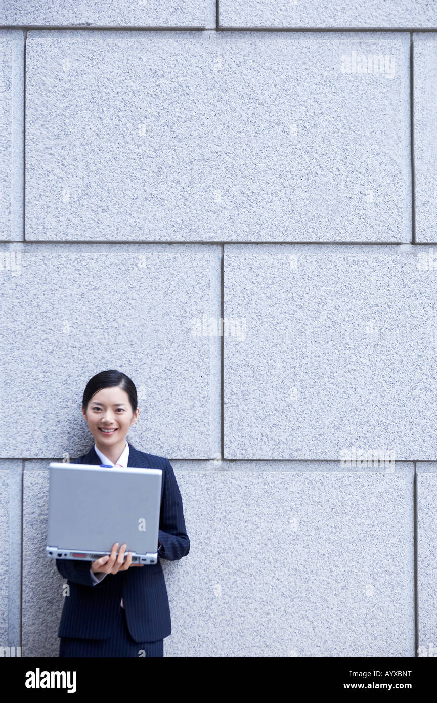 a woman using laptop computer with leaning over wall Stock Photo - Alamy