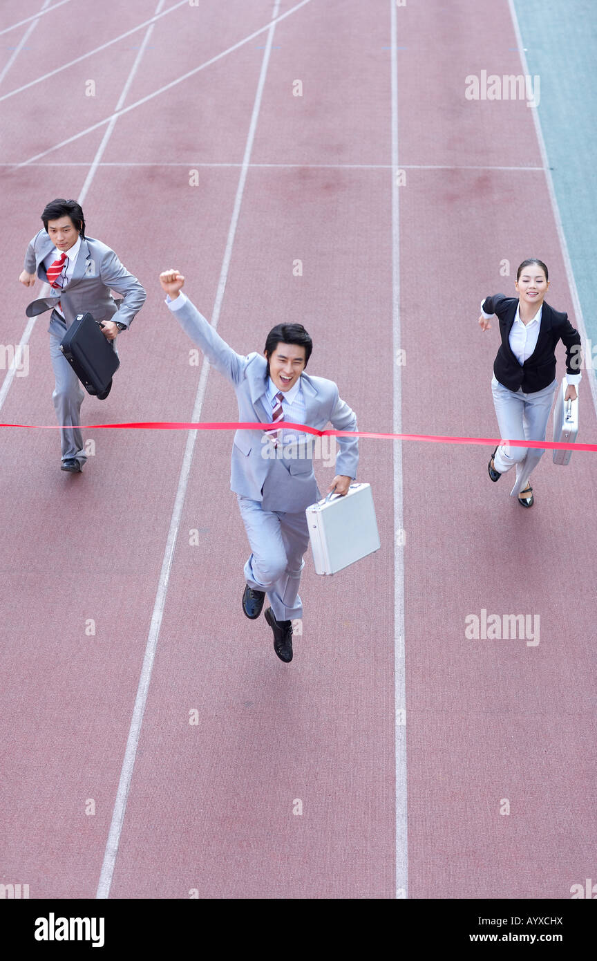 three person entering the finish line with a smile Stock Photo - Alamy