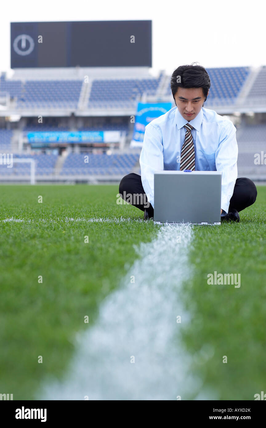 a man using laptop computer seated by playgound in an arena Stock Photo ...