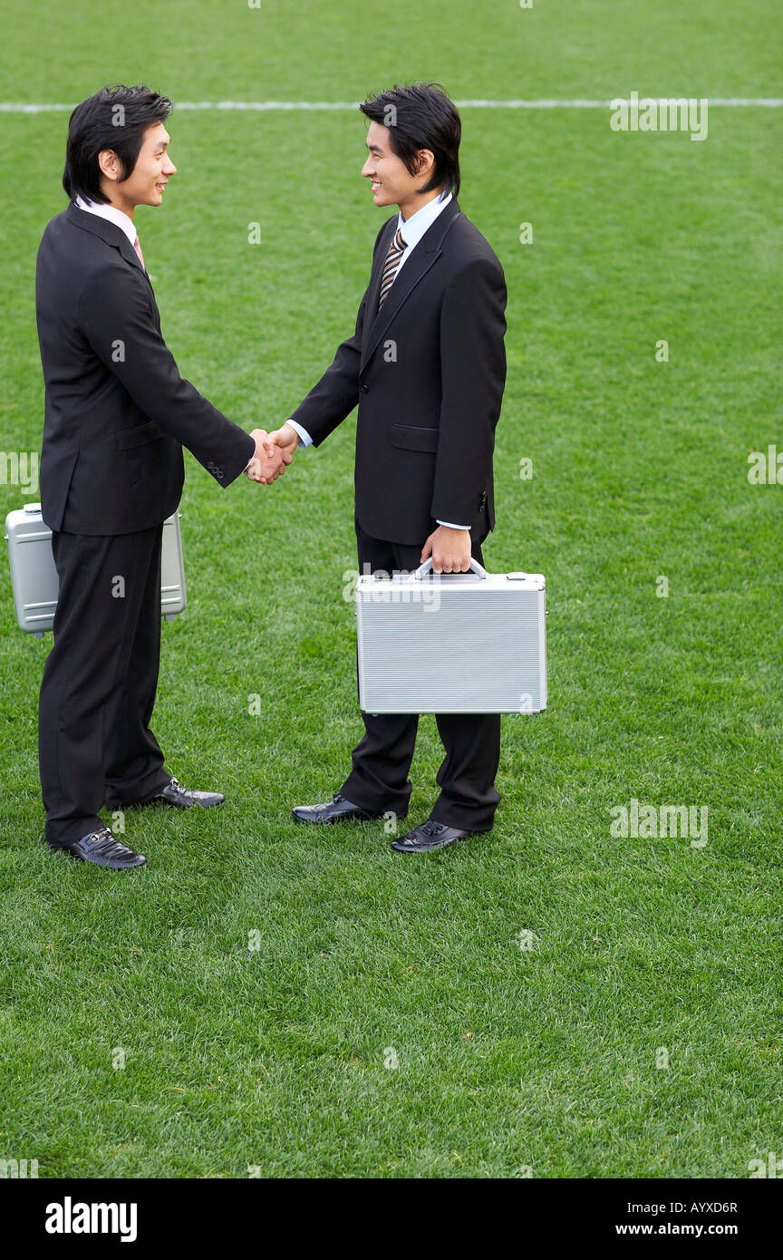 two men making a shakehand with holding in grass field Stock Photo - Alamy