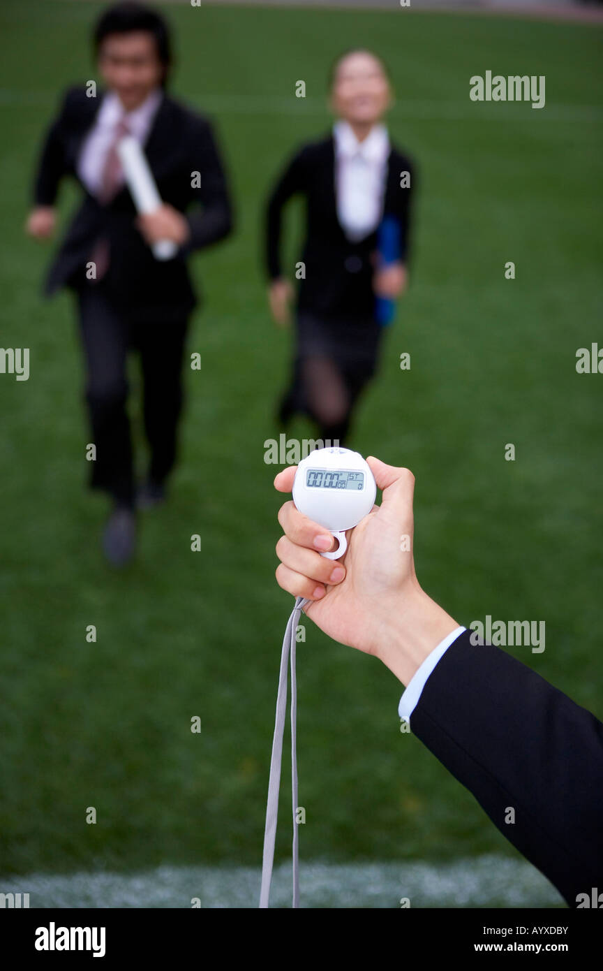 two person running and stop watch held by a hand Stock Photo - Alamy