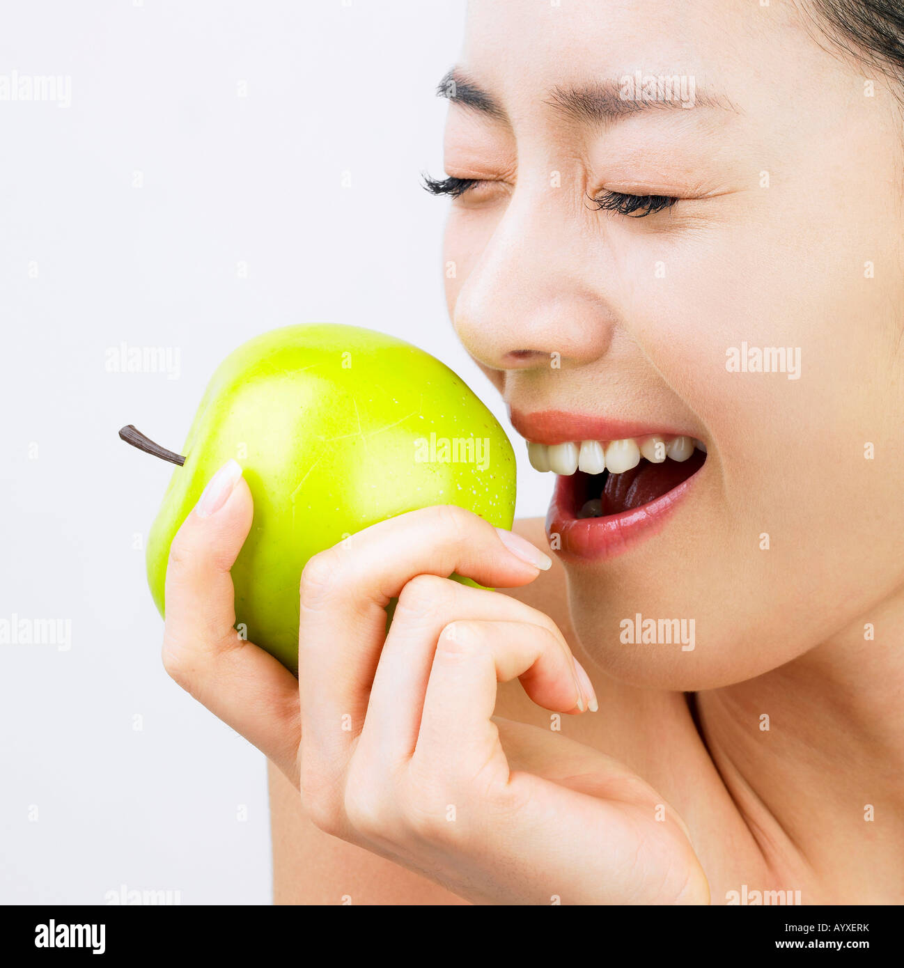 a woman's face holding a apple with winking at Stock Photo - Alamy
