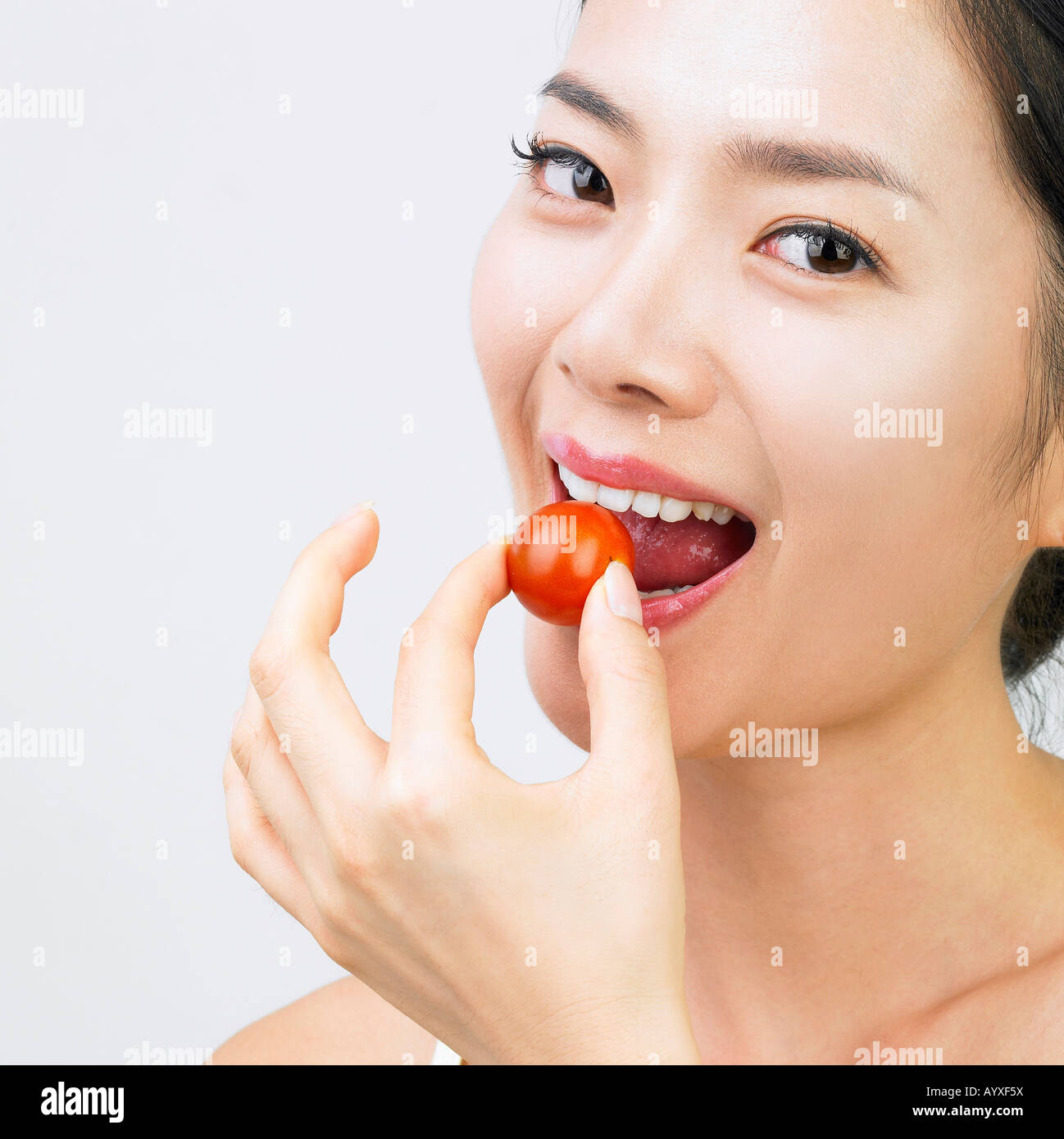 a woman's face eating a small tomato Stock Photo - Alamy