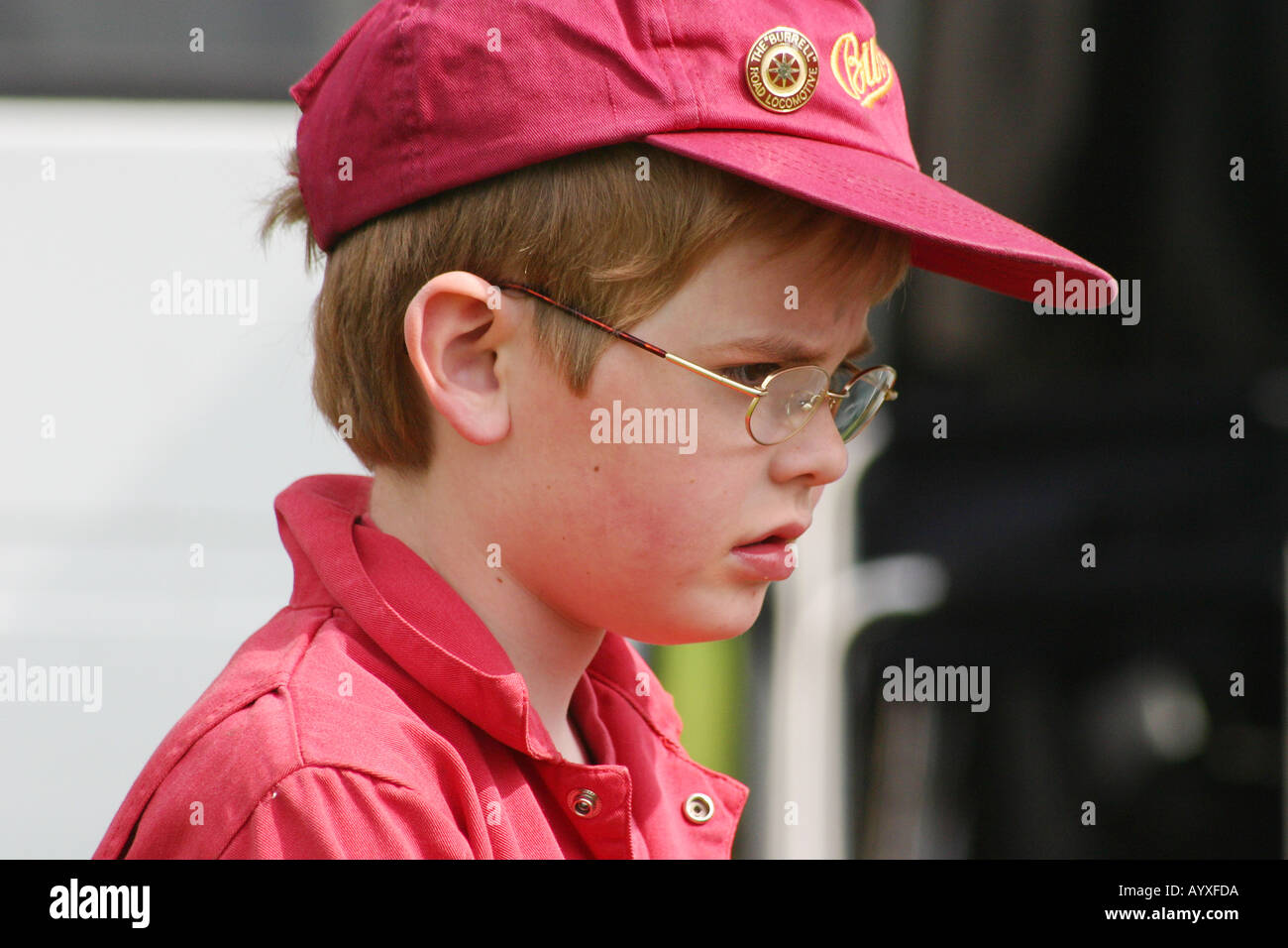 Young boy in overalls and cap working on steam engine at model ...