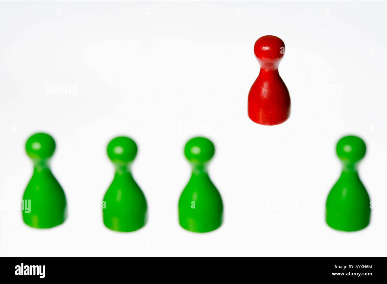 Red game piece standing beside green ones Stock Photo - Alamy
