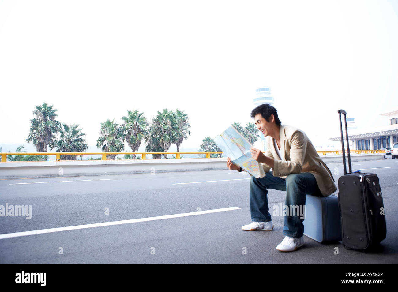 a man seeing a map with sitting on a suitcase Stock Photo - Alamy