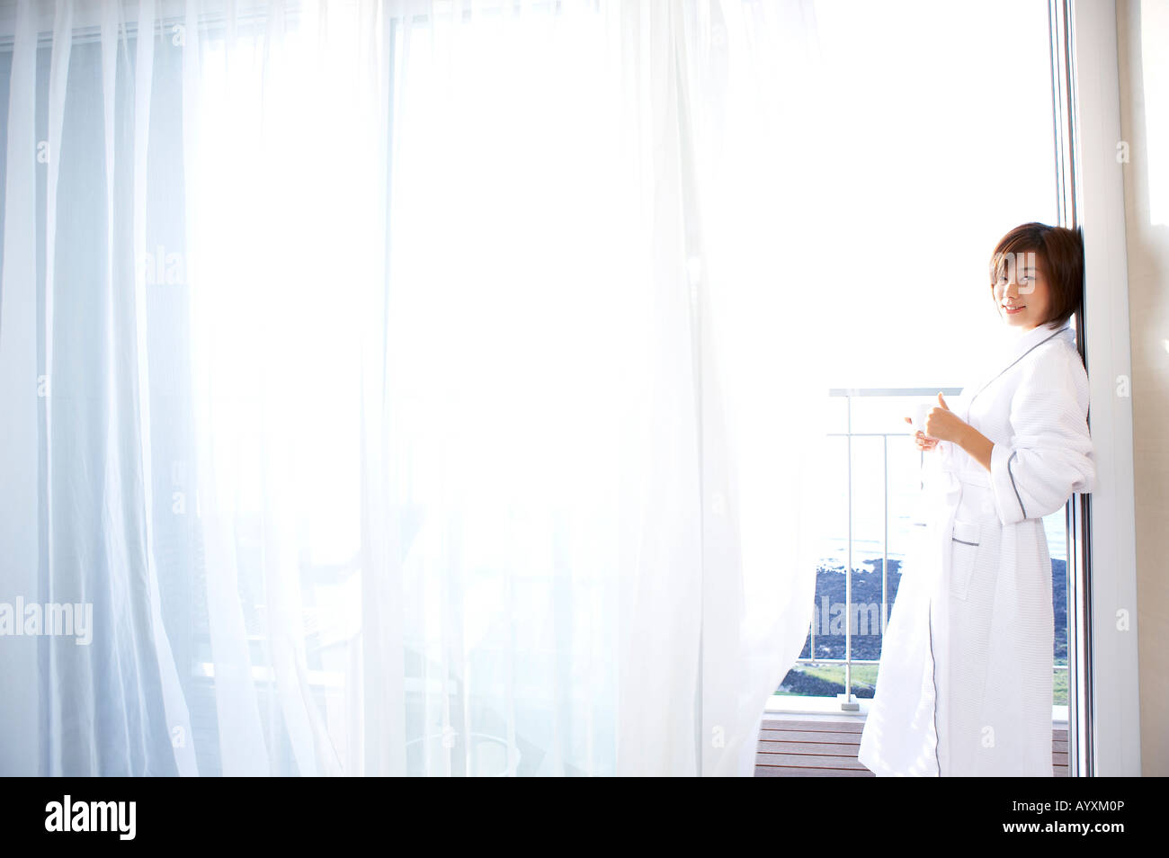 a woman leaning against window sunlight shines Stock Photo - Alamy