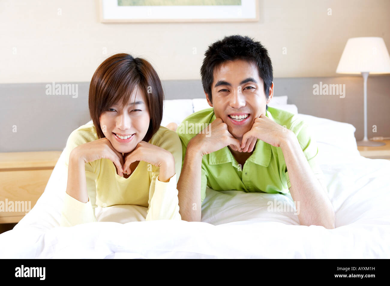 a smiling couple lay down on the bed Stock Photo - Alamy