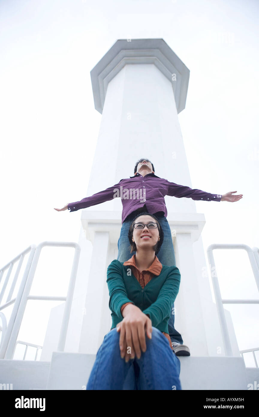 a woman unfolding her arms in front of the lighthouse and woman sitting ...
