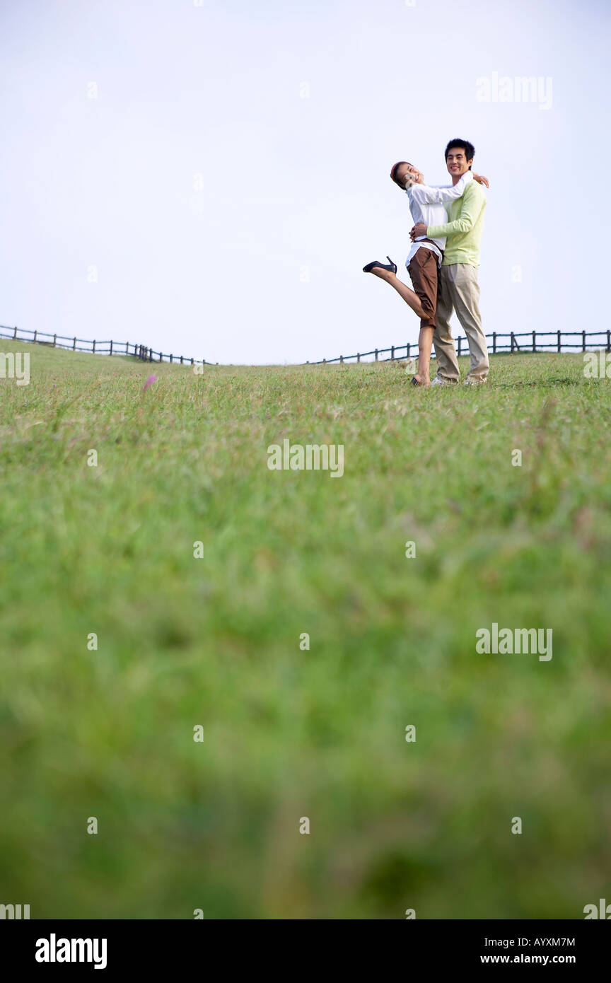 a couple hugging each other in the grass field Stock Photo - Alamy