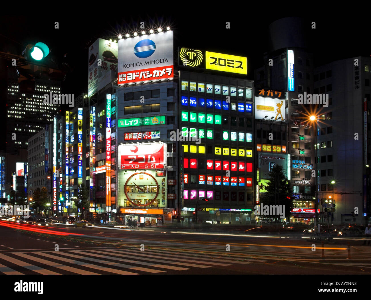 A pedestrian crossing in Shinjuku, Tokyo at night with bright lights ...