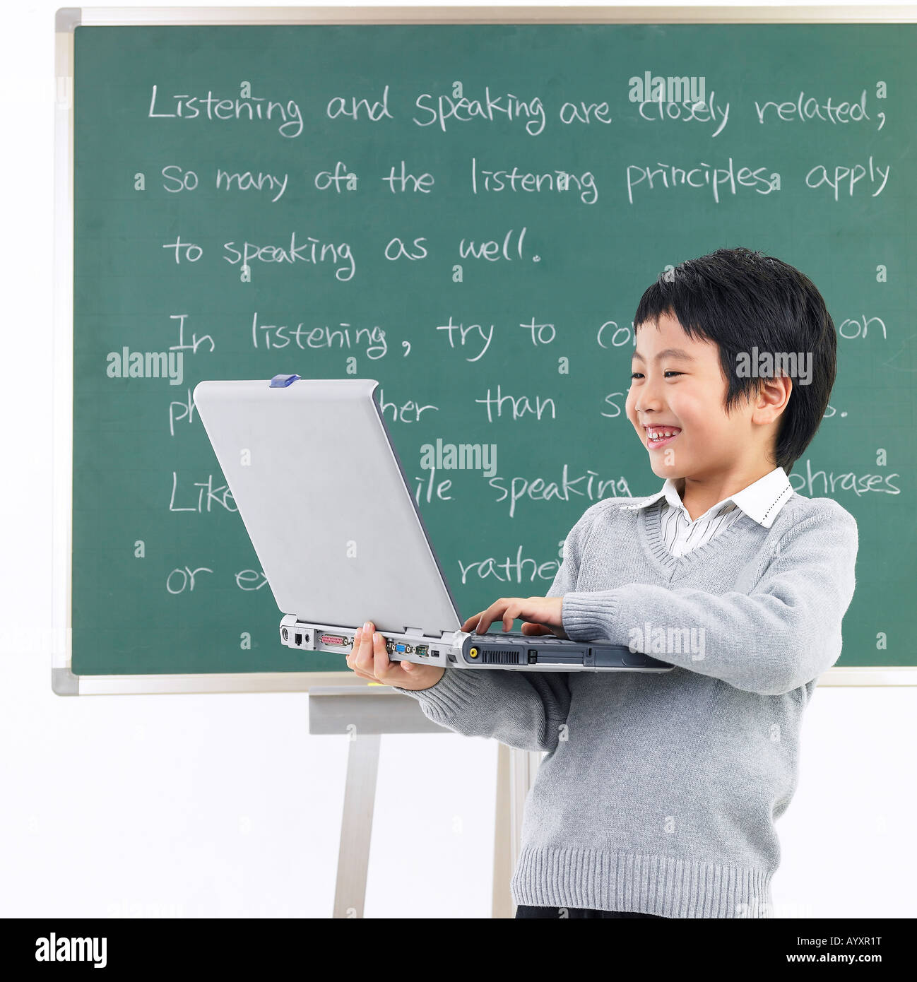 a boy using laptop computer in front of board Stock Photo - Alamy