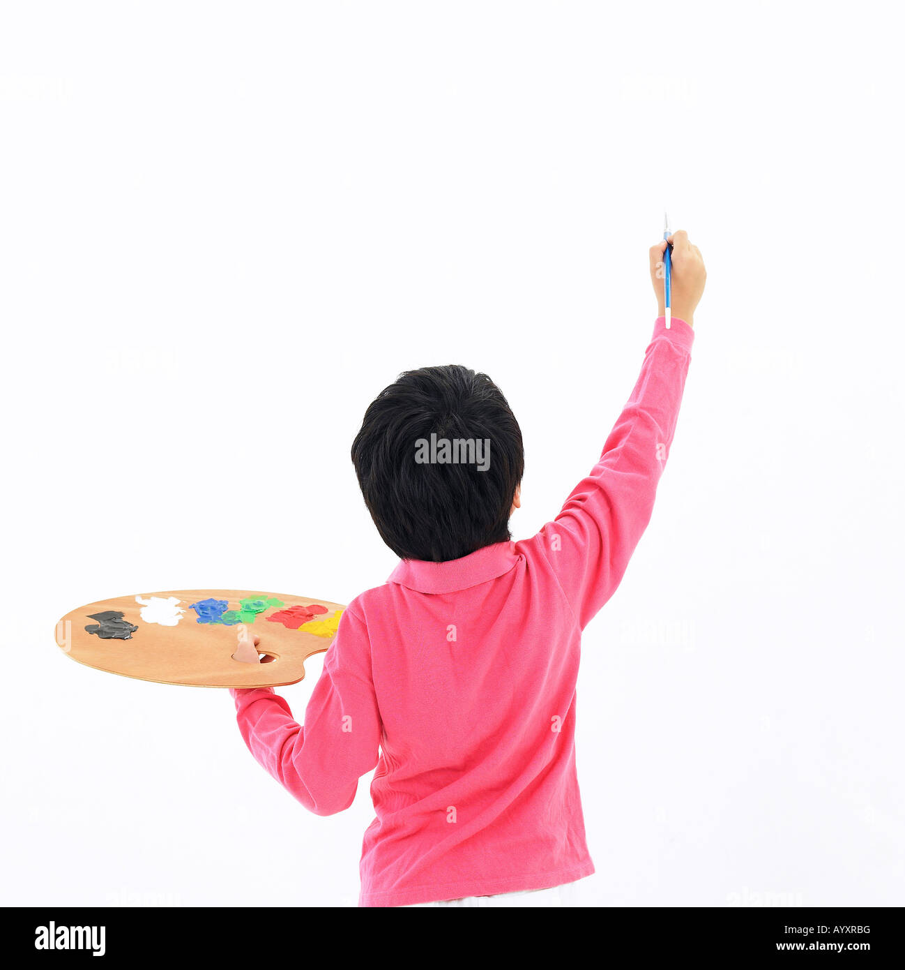 back view of a boy drawing a picture on white wall with holding a ...