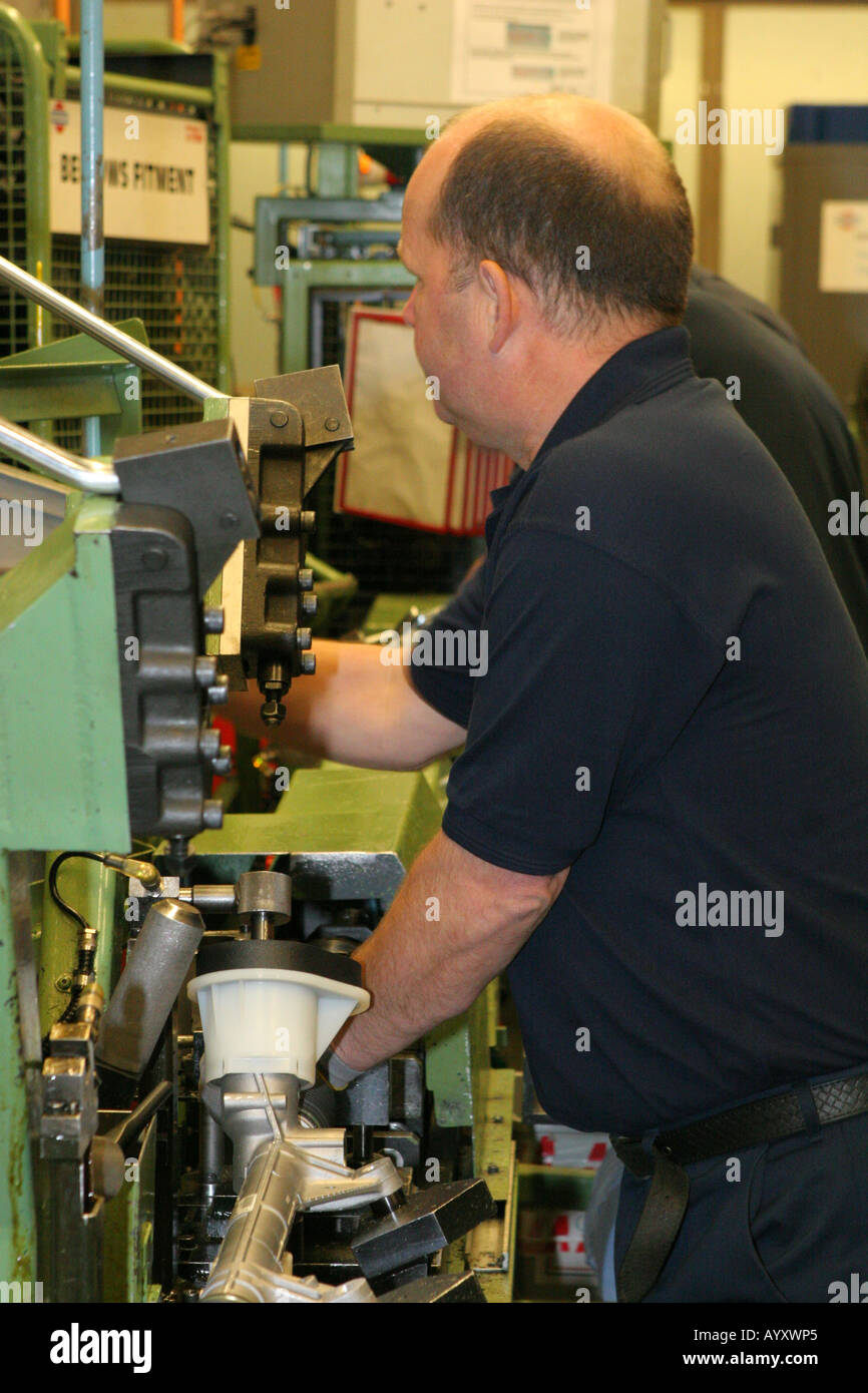 Factory workers working on a production line manufacturing car motor ...